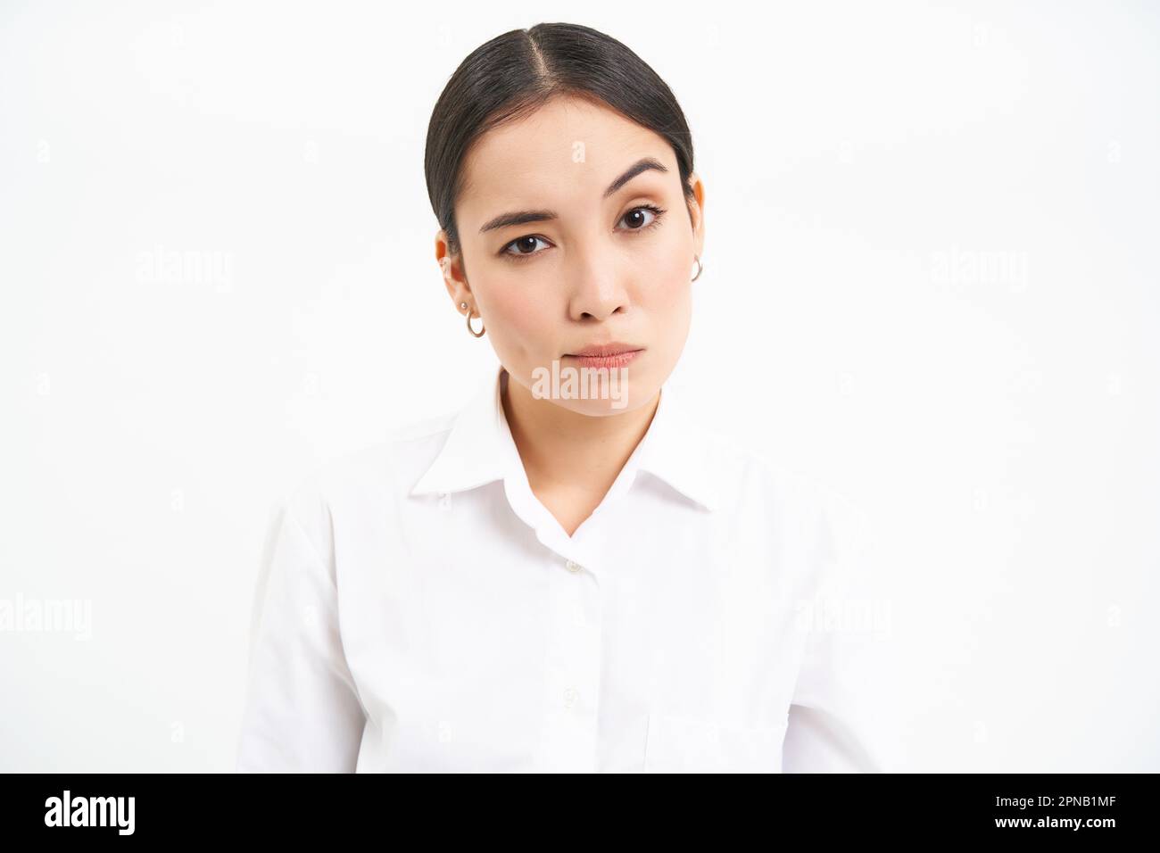 Portrait of skeptical asian woman, looks unamused and serious at camera ...