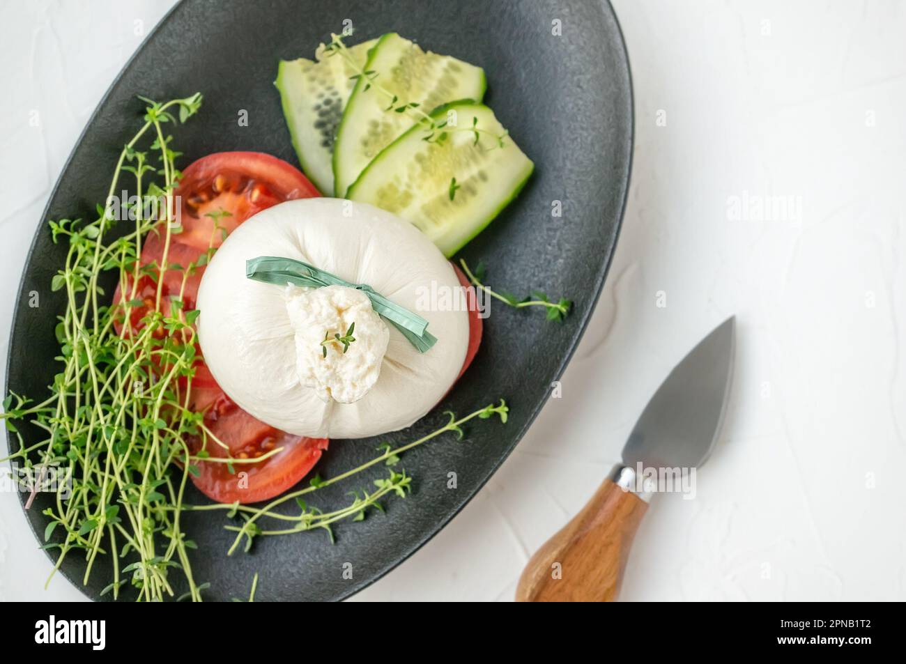 Italian cheese burrata, tomatoes and vegetables close-up. A layer of ...
