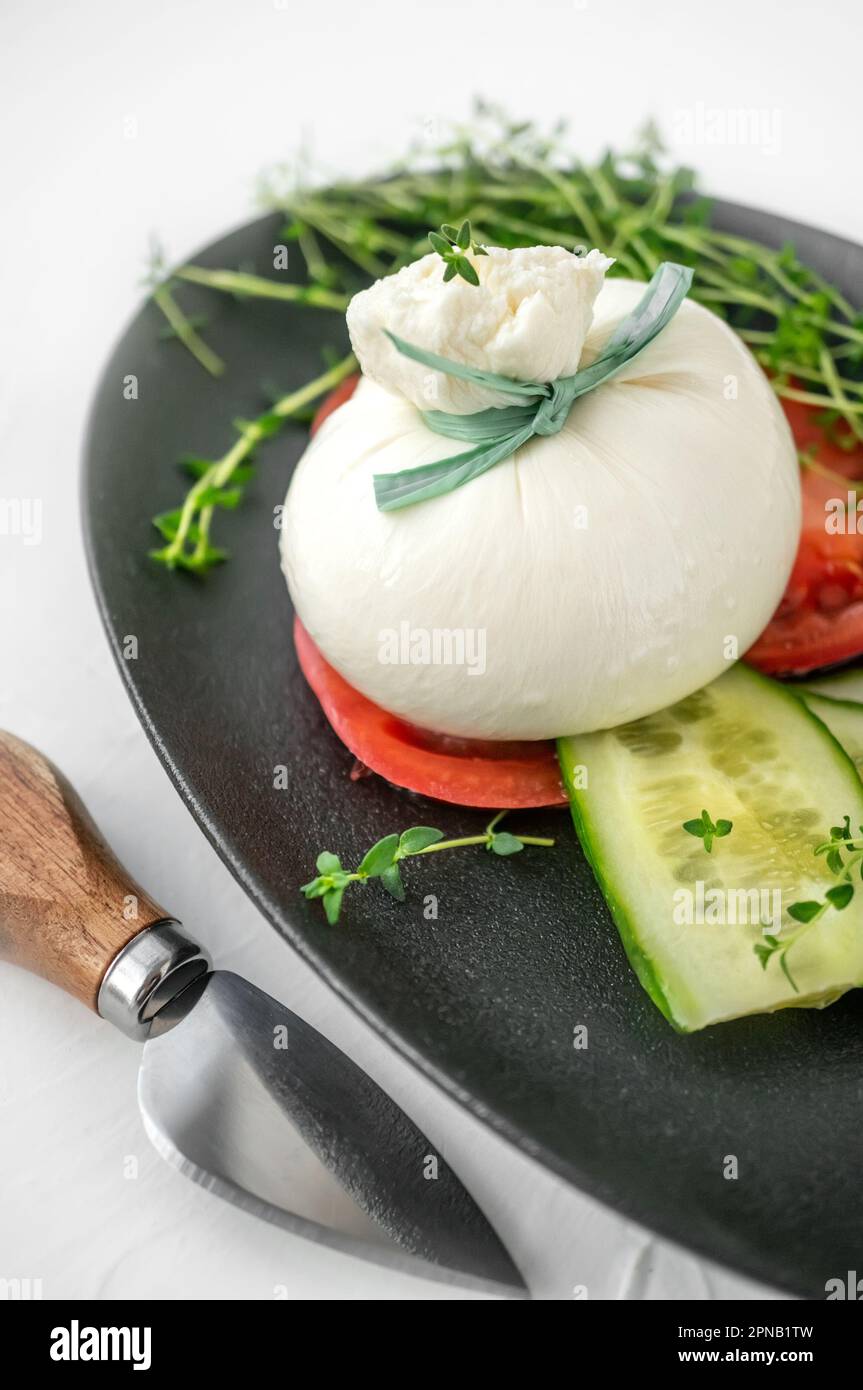 Italian cheese burrata, tomatoes and vegetables close-up. A layer of ...