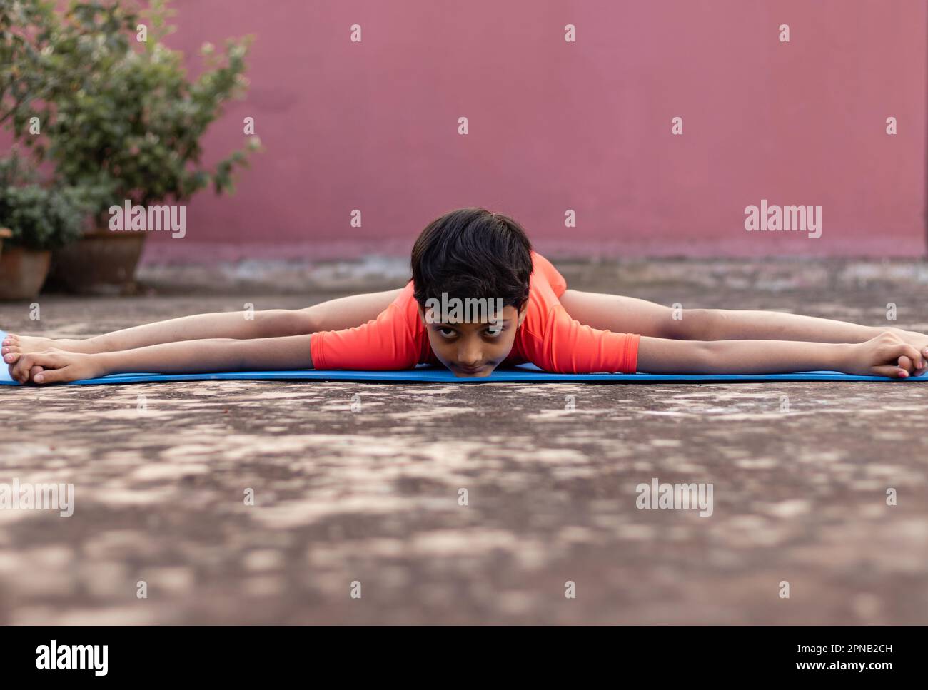 An Indian girl child practicing bhumasana yoga on yoga mat outdoors ...