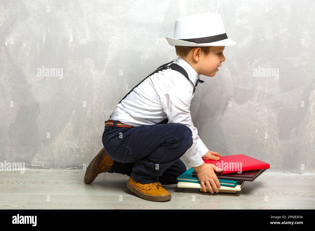 Elementary school student carrying notebooks over a gray background ...