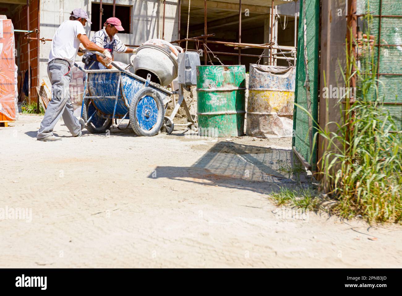 Teamwork, workers are pouring fresh mortar in wheelbarrow from mortar ...