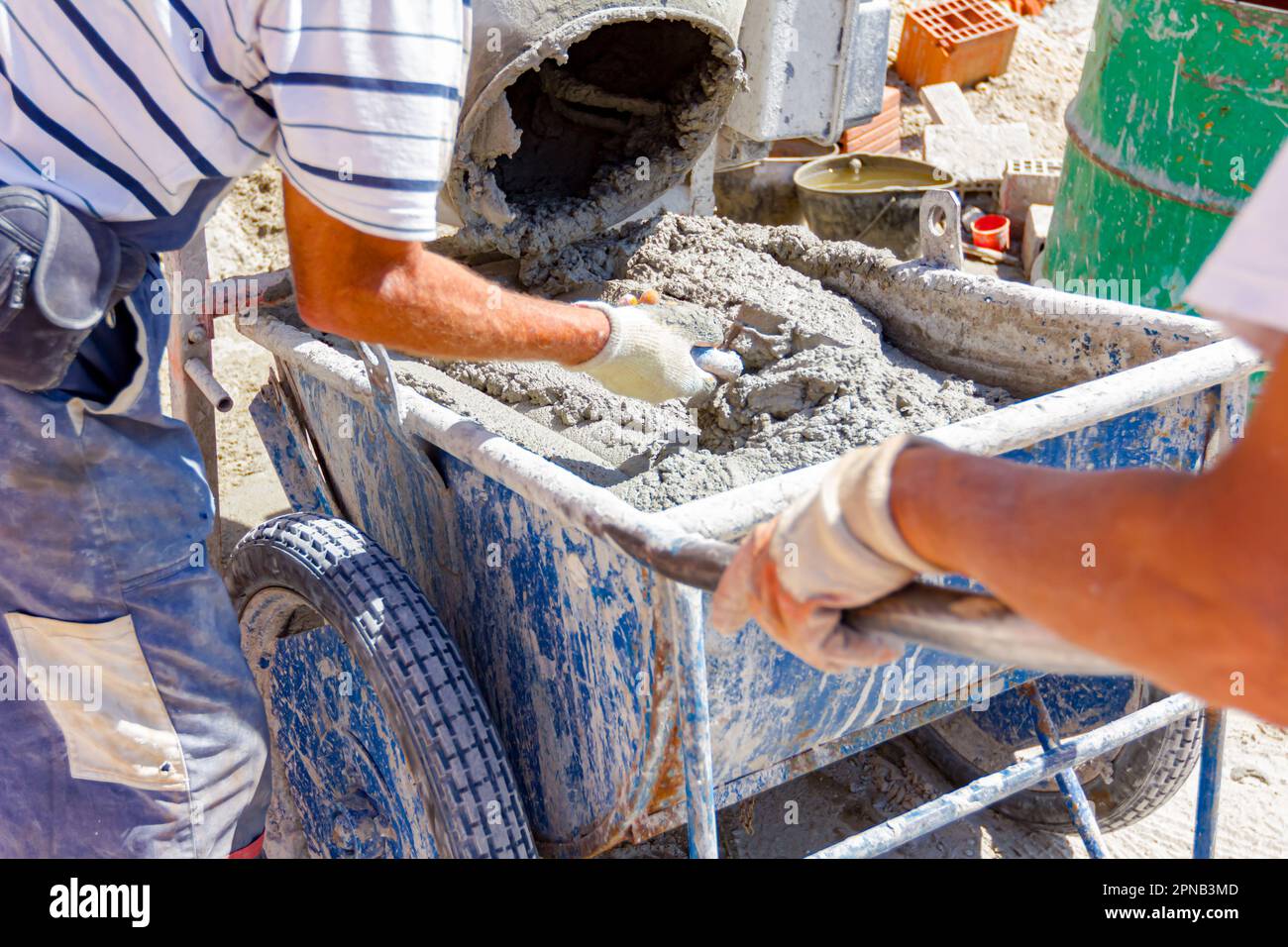 Teamwork, workers are pouring fresh mortar in wheelbarrow from mortar ...