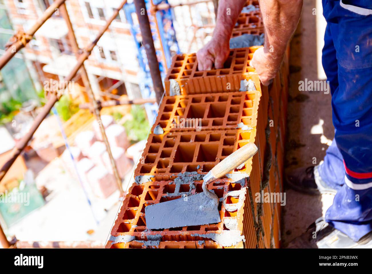 Spatula, trowel placed on red ceramic block, mason bricklayer worker is ...