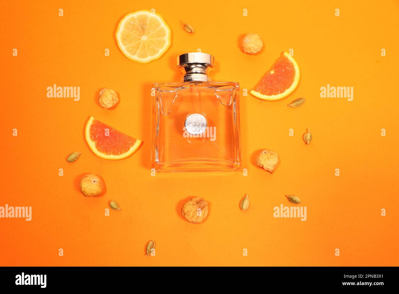 A Versace perfume bottle with orange slices against an orange ...