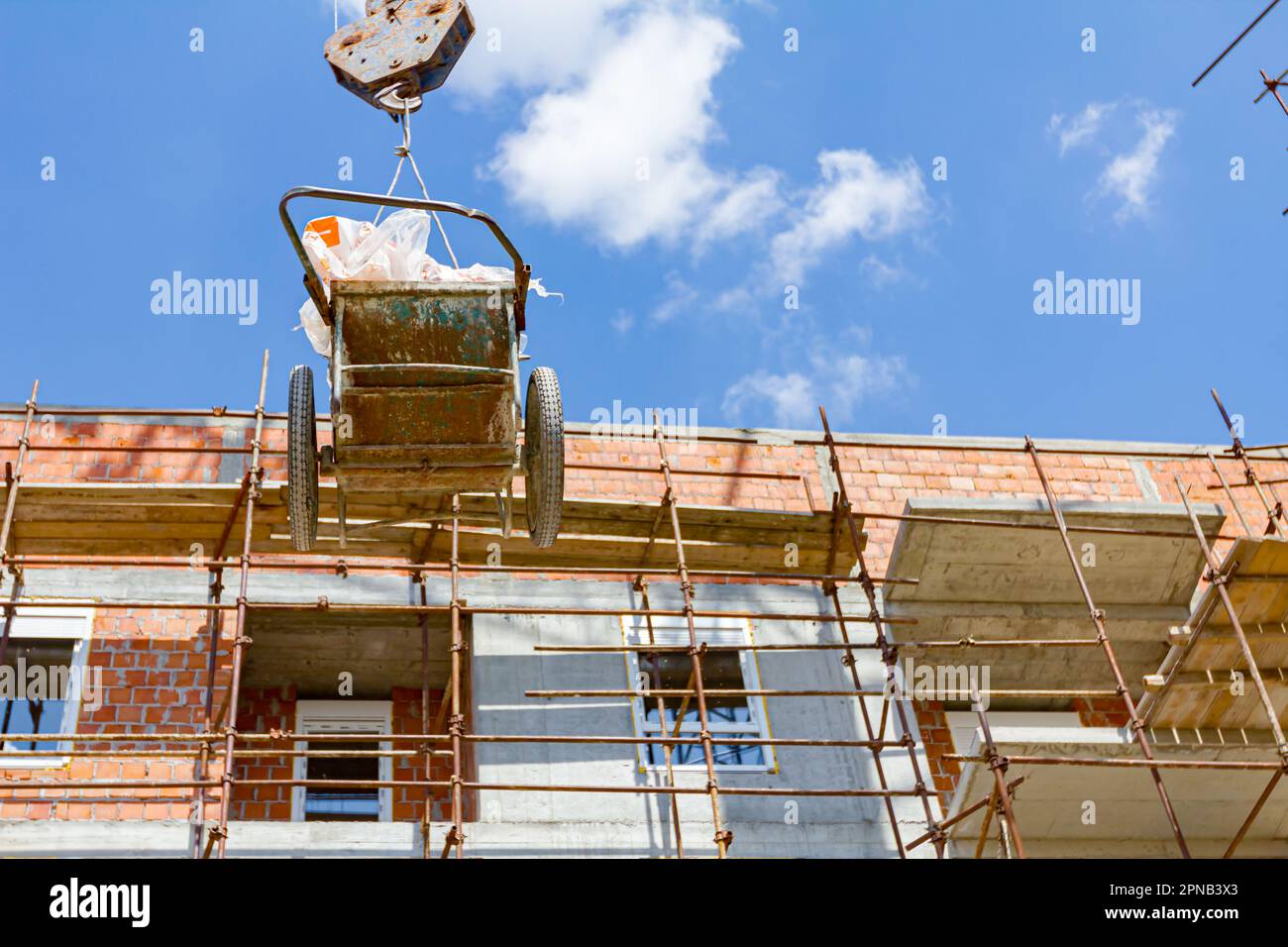 Shot from below of crane that puts down on ground wheelbarrow full of ...