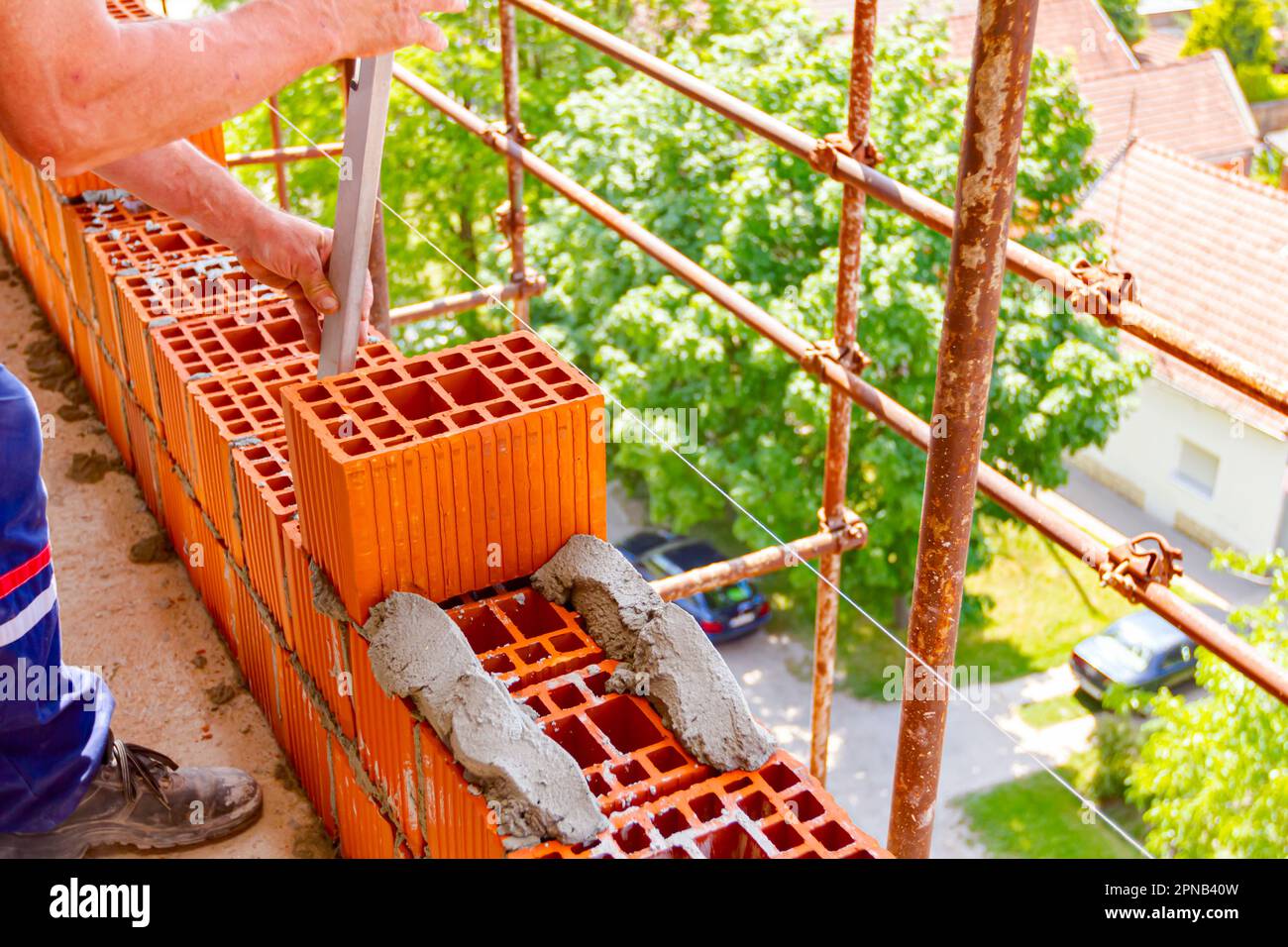Builder is using a spirit level to check new red brick wall made of red ...