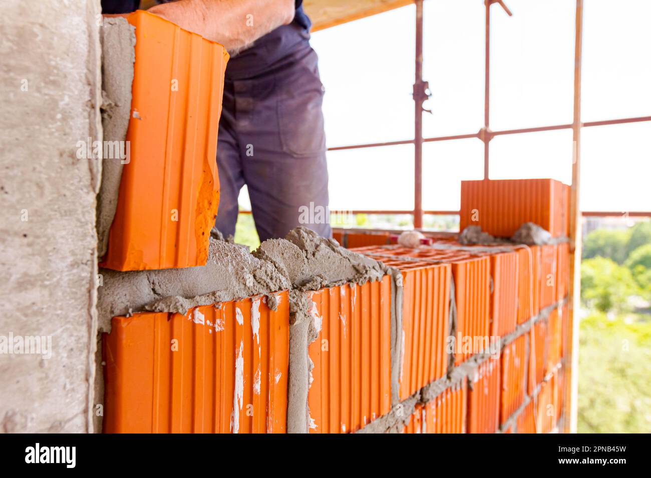Mason, bricklayer worker is using red blocks to mount a wall at ...