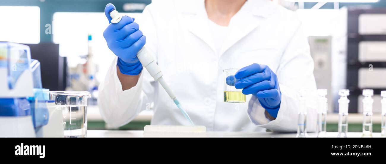 Scientist with dropper dripping liquid into a test tube in scientific ...