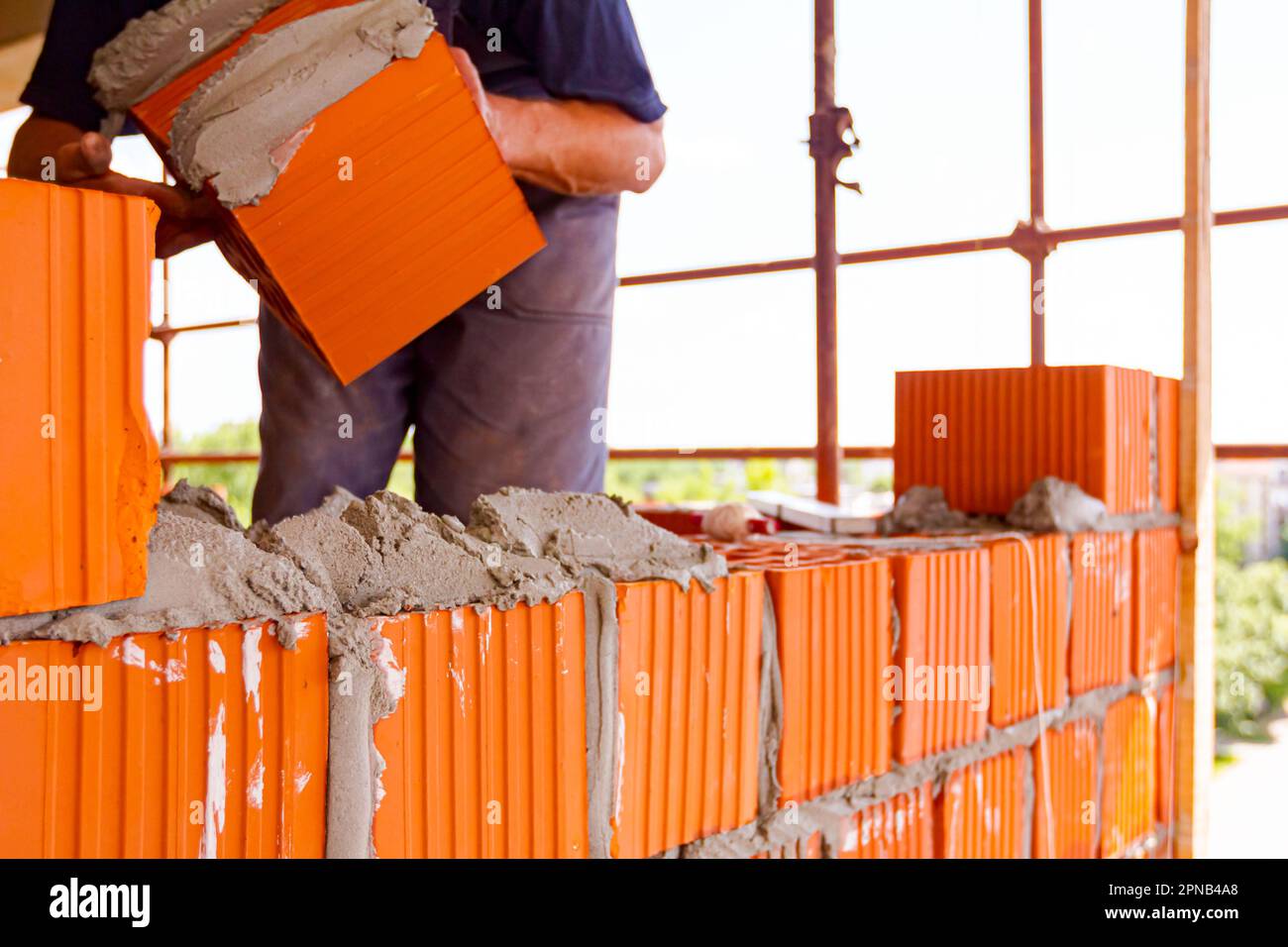 Mason, bricklayer worker is using red blocks to mount a wall at ...