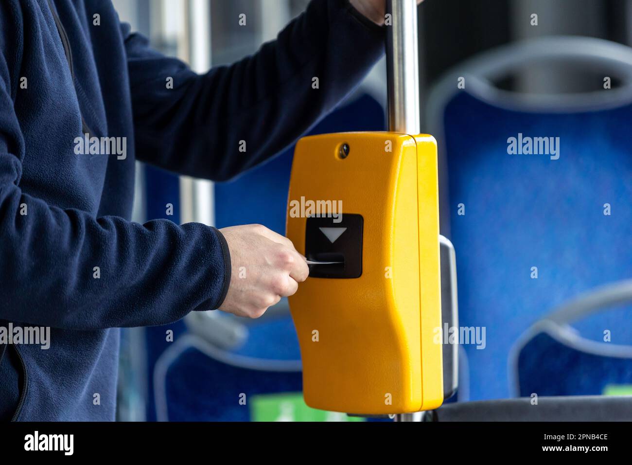 Young man hand inserts the bus ticket into the validator, validating ...