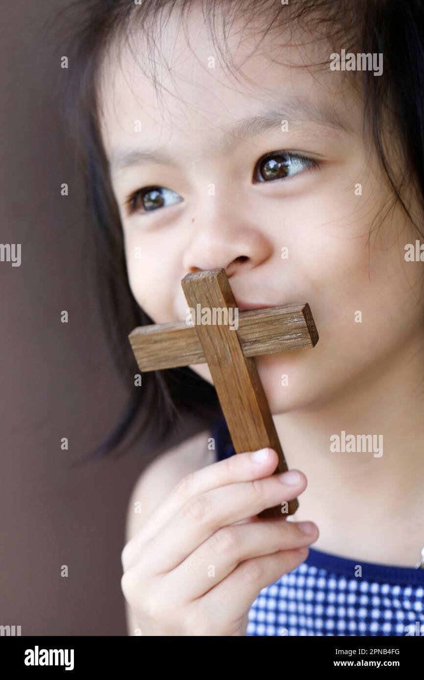 Teenage girl praying to God holding a wooden cross. Concept of hope ...