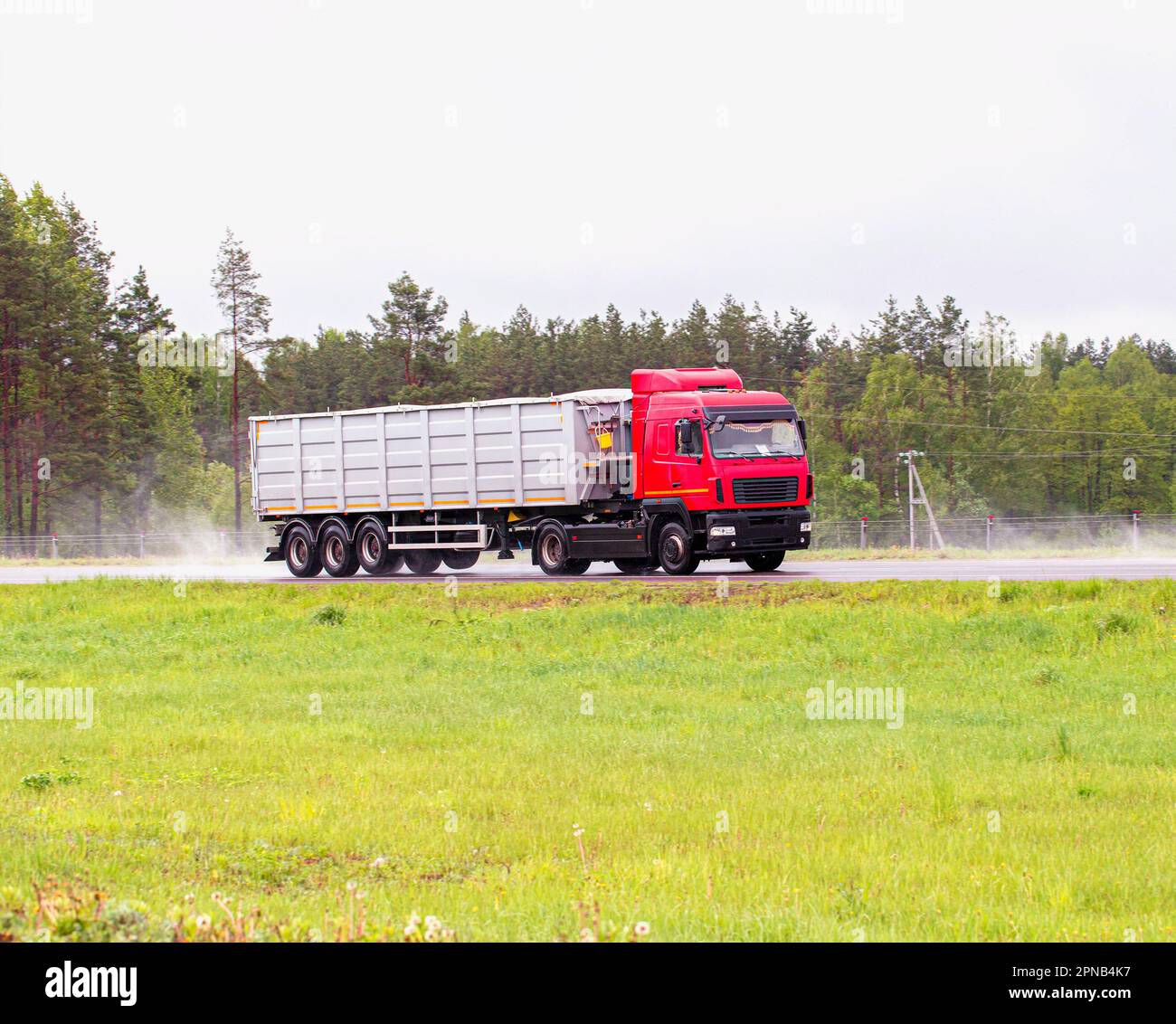 A truck with a semi-trailer for bulk cargo rides in rainy weather ...