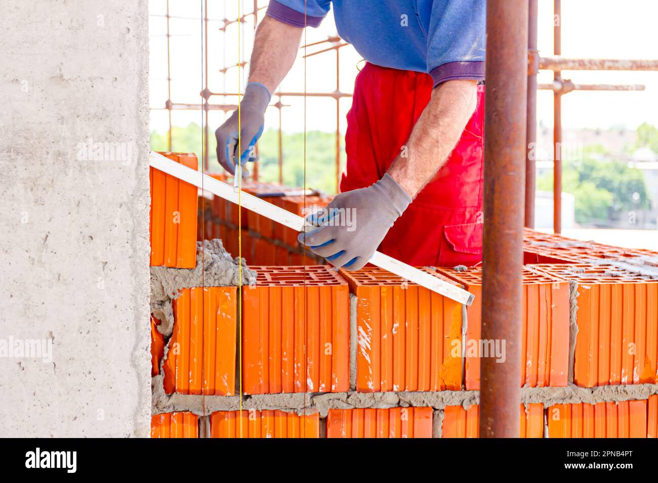Builder is using a spirit level to check new red brick wall made of red ...