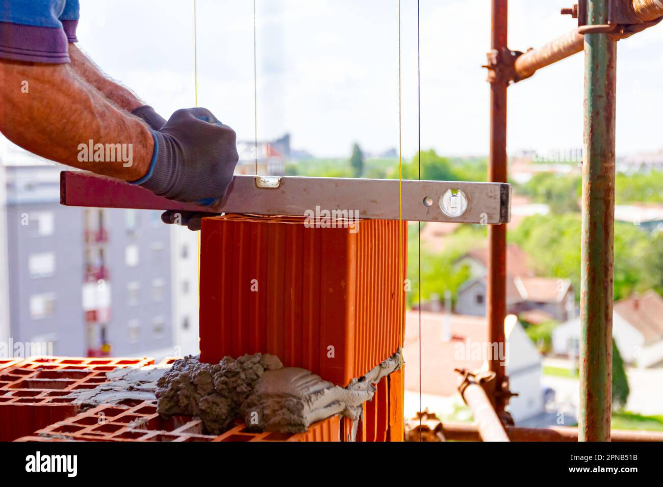Builder is using a spirit level to check new red brick wall made of red ...