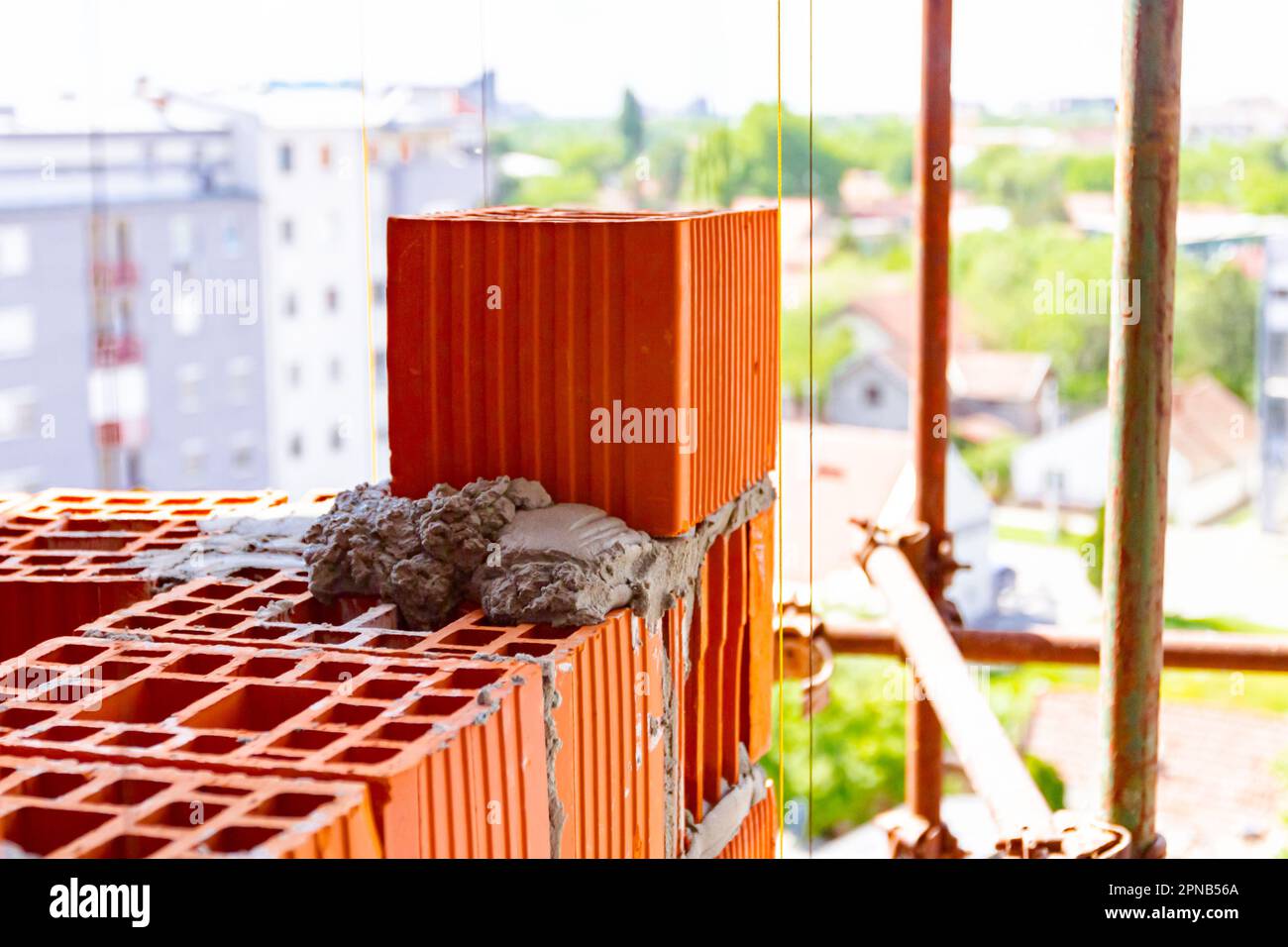 Wall edge made of red blocks and mortar with rusty scaffold on ...