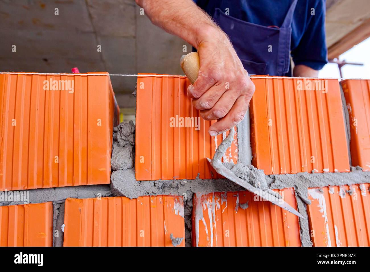 Worker is using spatula, trowel, to scrape off any excess mortar that ...