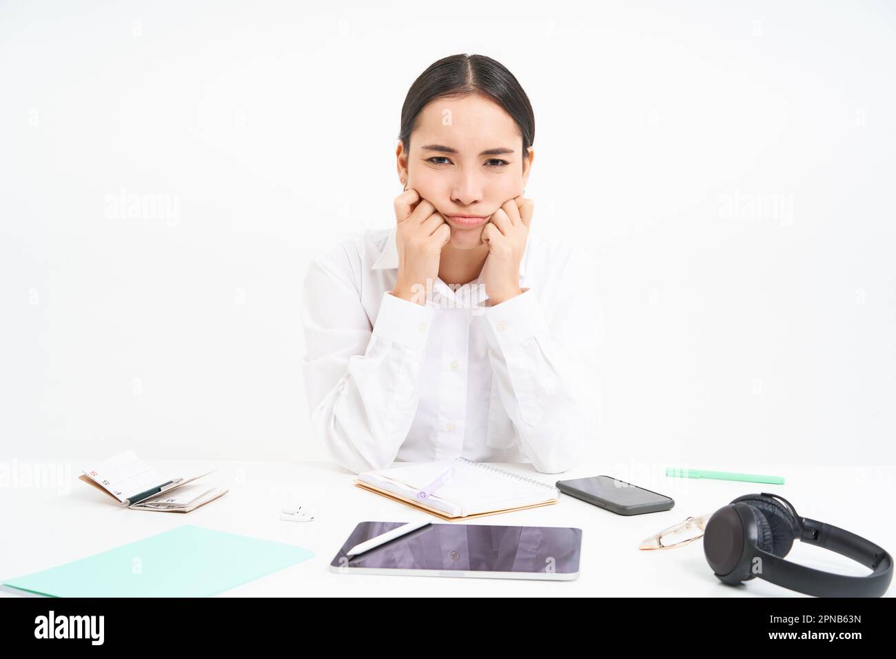 Sad and grumpy asian woman at workplace, sits with digital tablet and ...