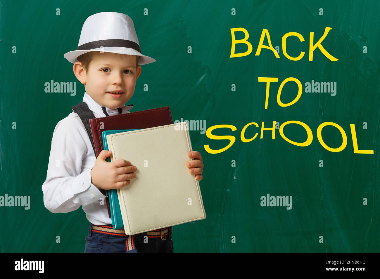 Back to school. Funny little boy in glasses pointing up on blackboard ...