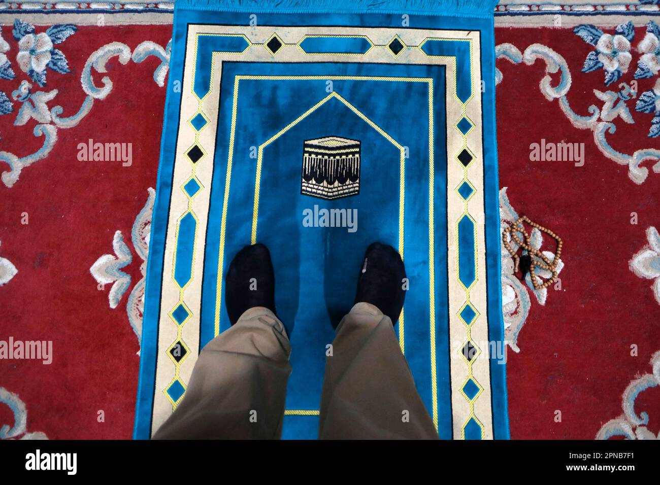A Muslim man during prayers at a mosque. View on feet and prayer rug ...