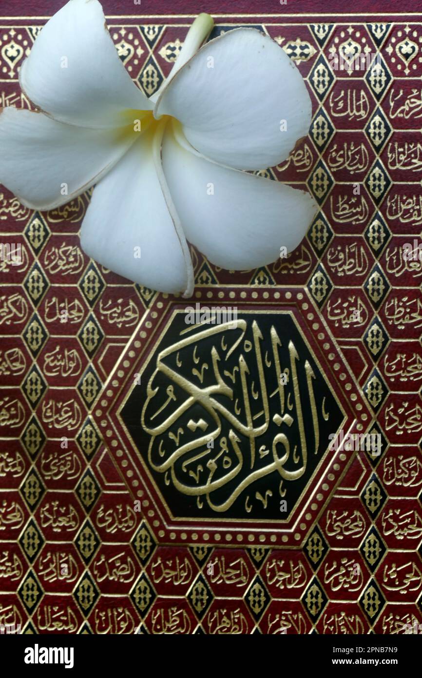 Cover of the Holy Quran (Koran) and a white magnolia. 99 names of Allah ...