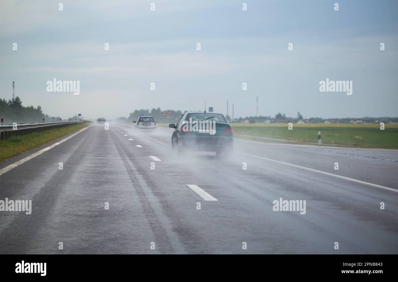 Traffic from cars drives on a highway slippery from rain in cloudy rainy weather Stock Photo - Alamy