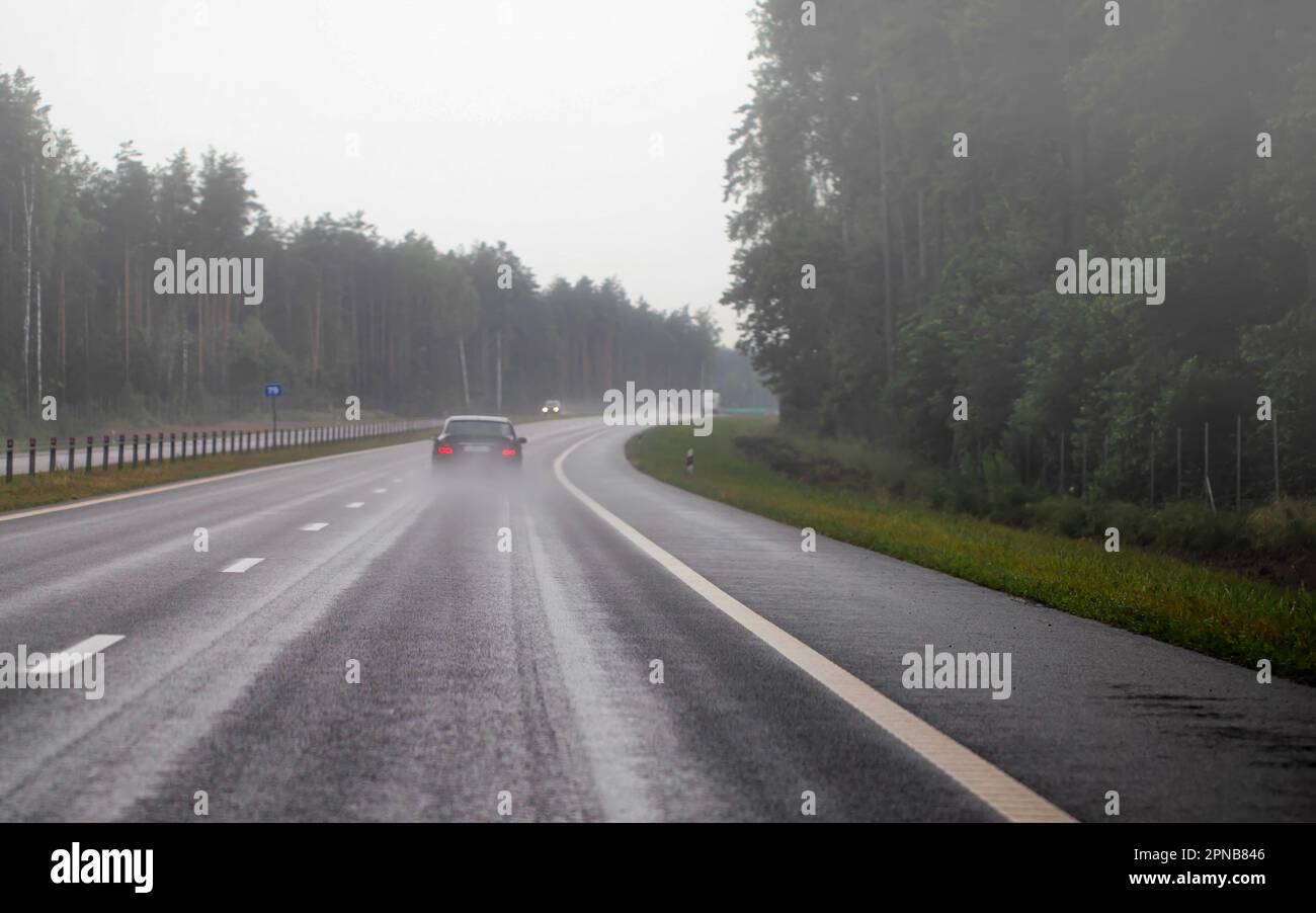 Traffic from cars drives on a highway slippery from rain in cloudy ...