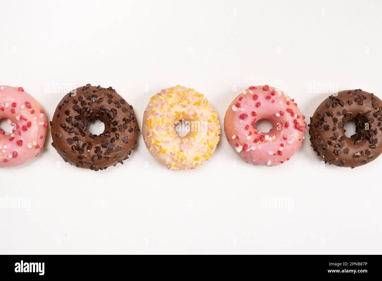 Five donuts in a row - white, pink and chocolate on a white background ...