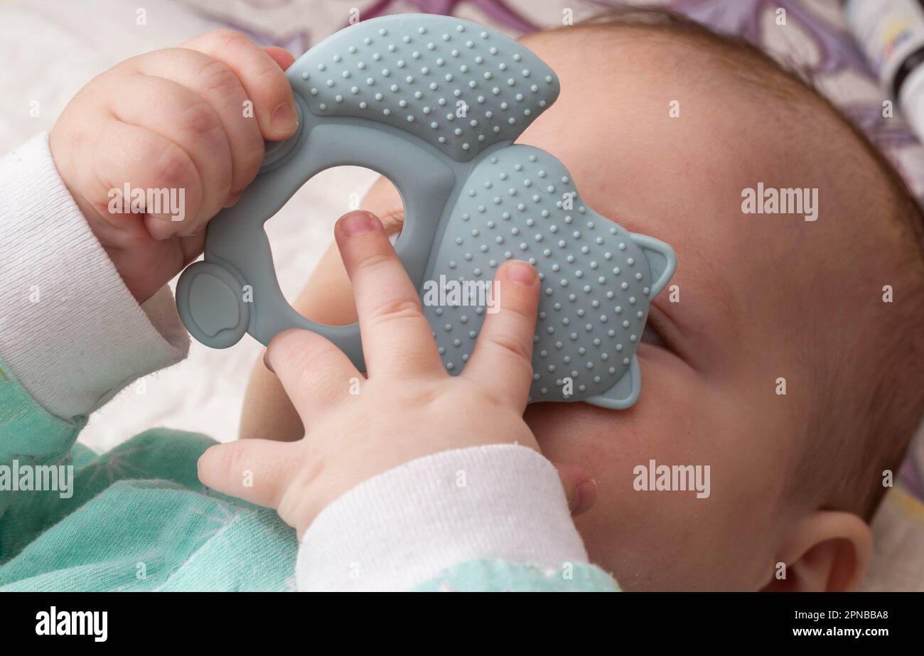 A baby boy plays with a teether during the eruption of the first teeth ...