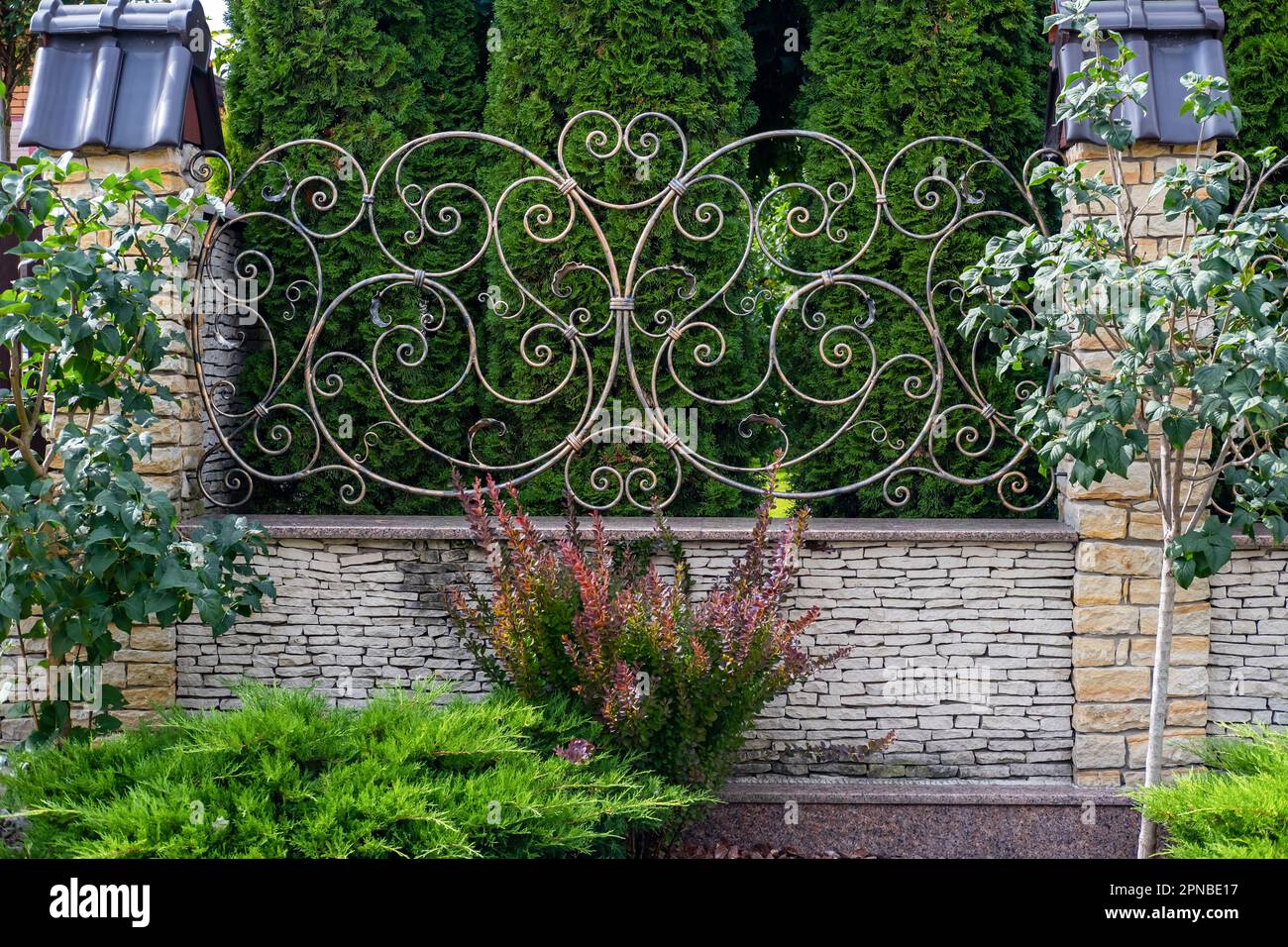 Iron wrought-iron fence between decorative brick columns in front of a ...