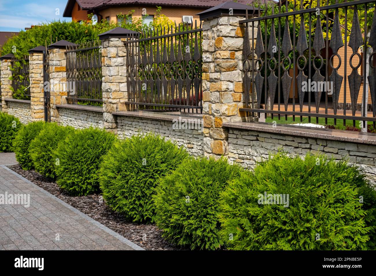 Iron wrought-iron fence between decorative brick columns in front of a ...