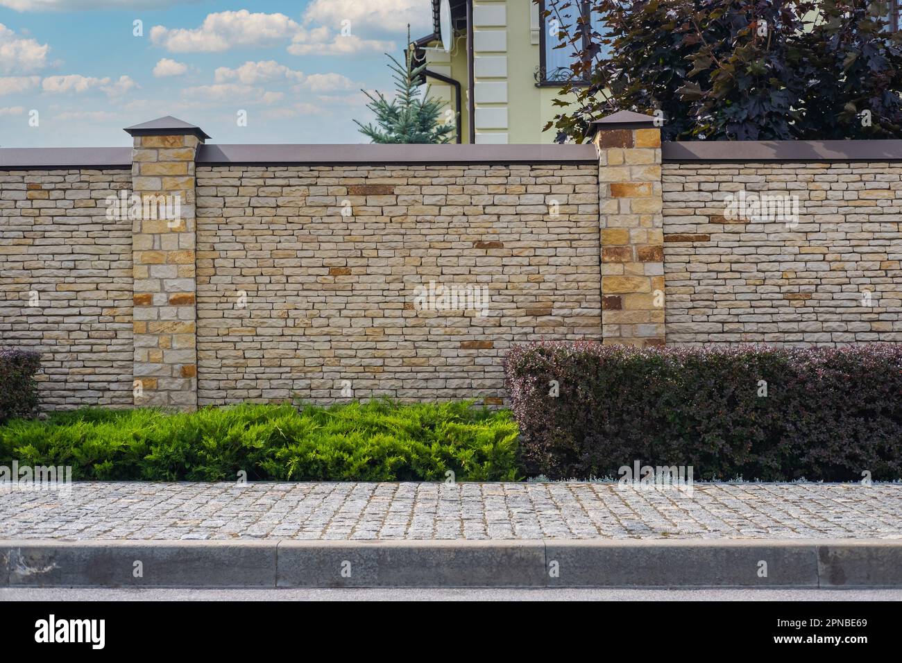 Modern brick pattern of light stone fence wall with posts in front of a ...