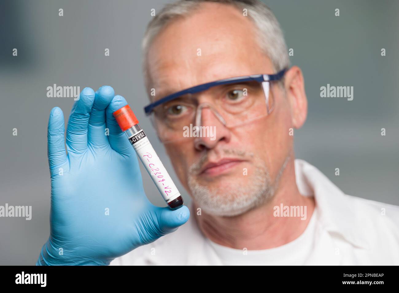 doctor or scientist is handling a blood test tube in front of a lab ...