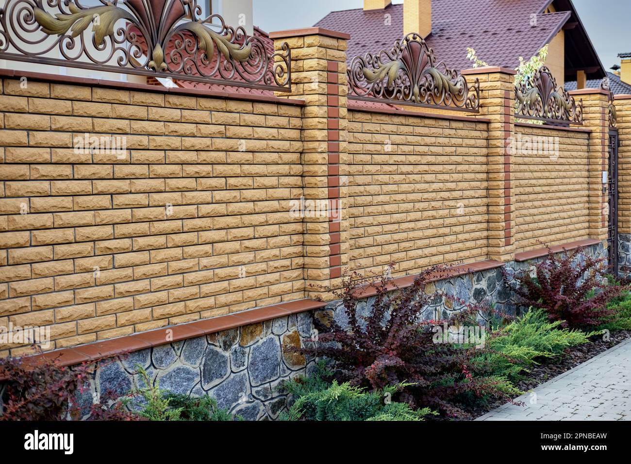 Decorative modern yellow brick fence with brick columns near a ...