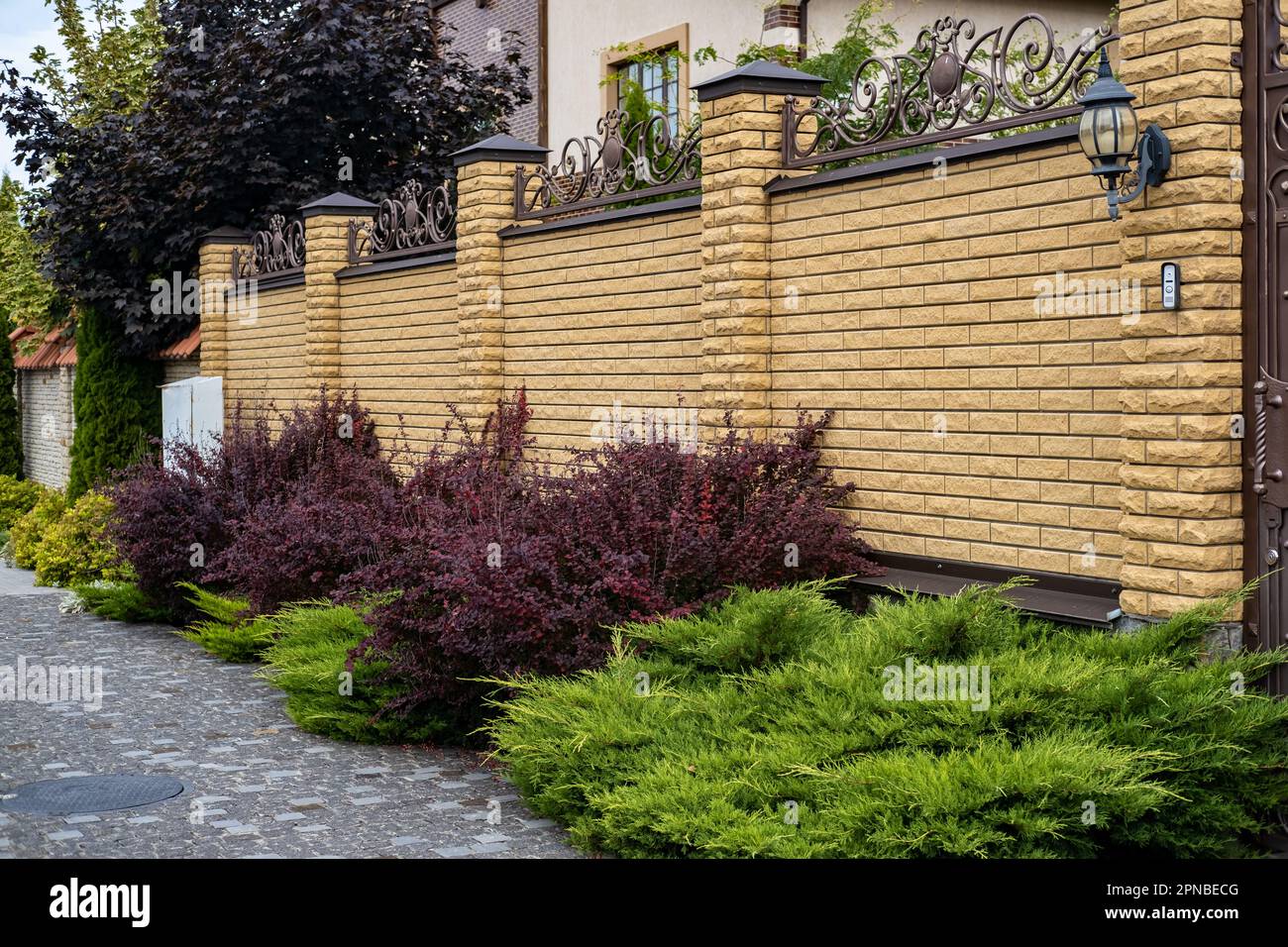 Decorative modern yellow brick fence with brick columns near a ...
