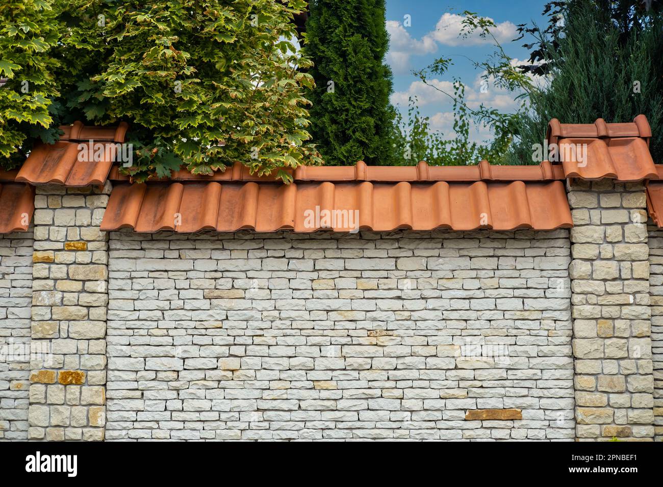 Modern brick pattern of light stone fence wall with tiles in front of a ...
