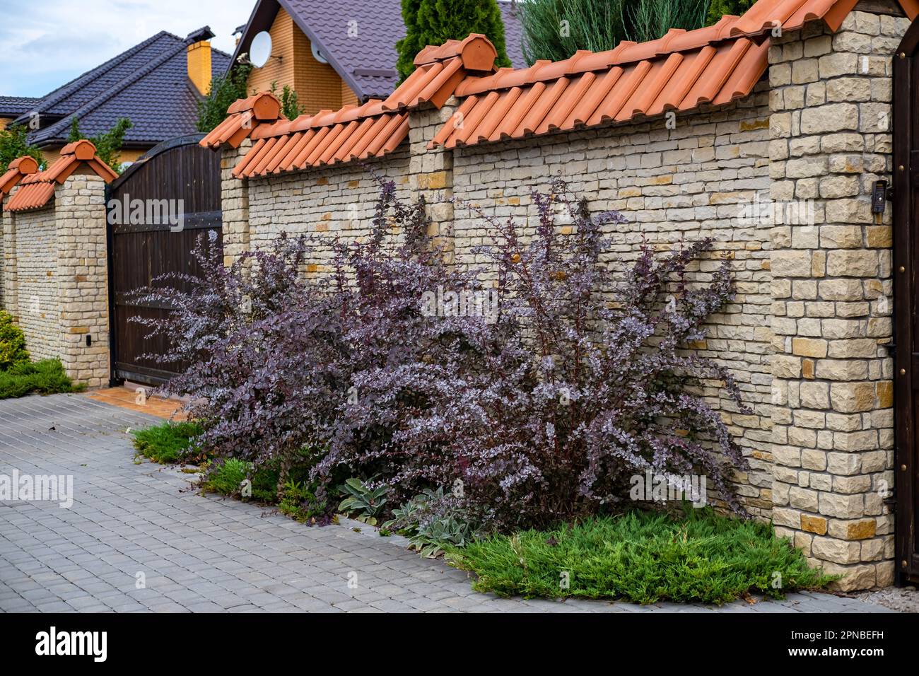 Modern brick pattern of light stone fence wall with tiles in front of a ...