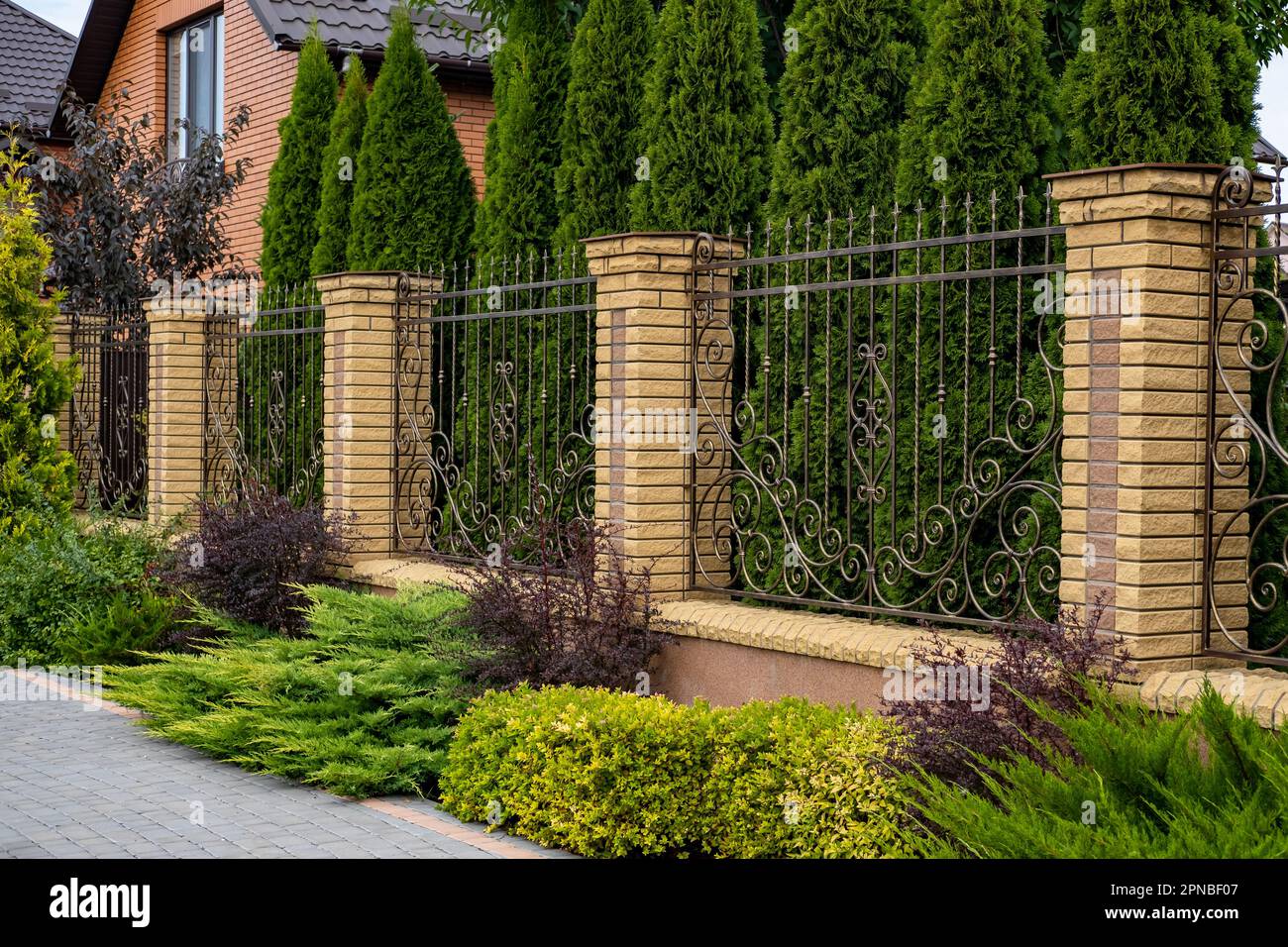 Iron wrought-iron fence between decorative brick columns in front of a ...