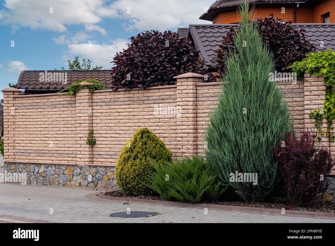 Modern brick pattern of light stone fence wall with posts in front of a ...