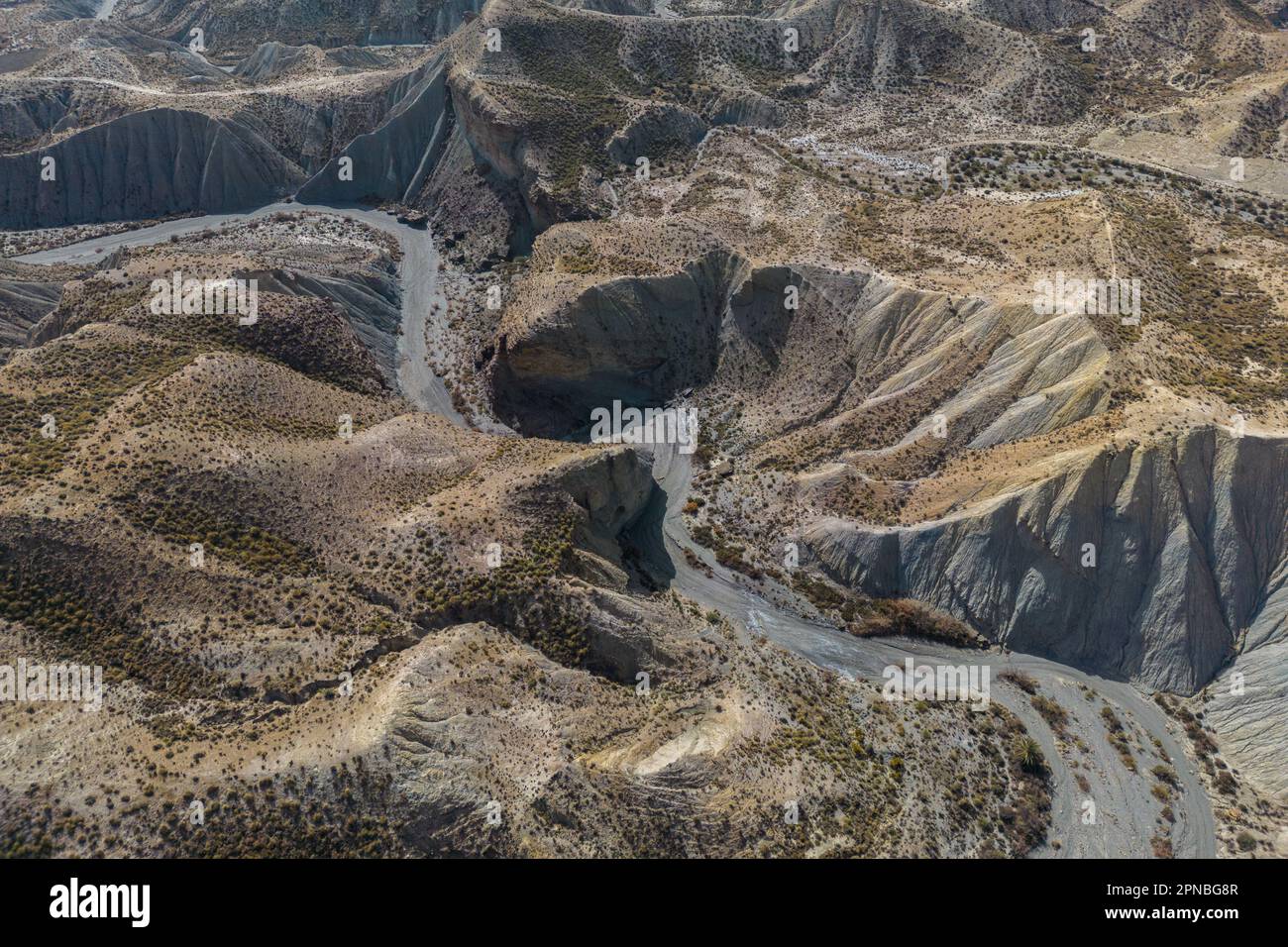 Aerial view of rough rocky mountains with dry river meandering through ...
