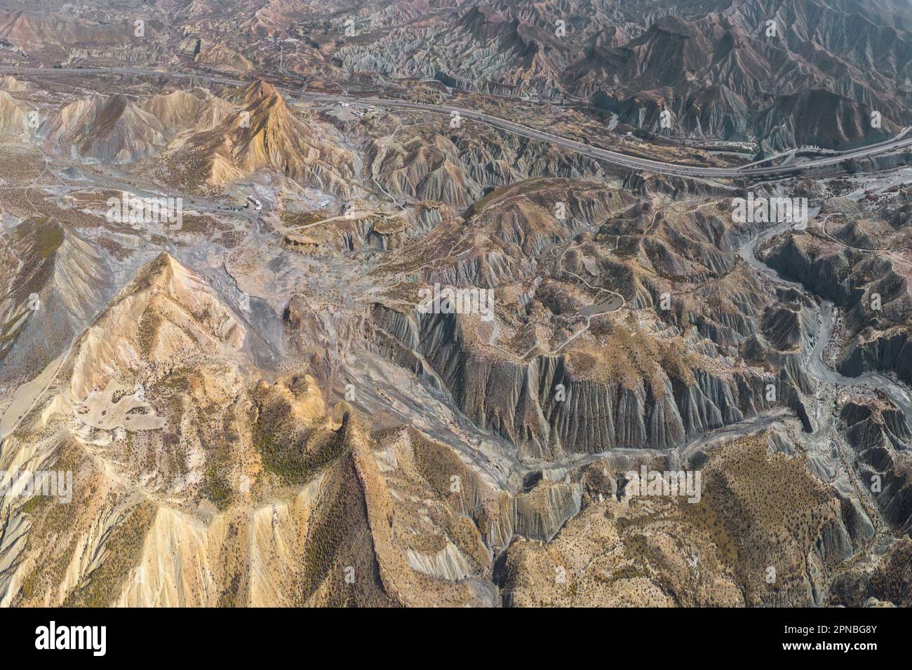 Aerial view of rough rocky mountains with dry river meandering through ...