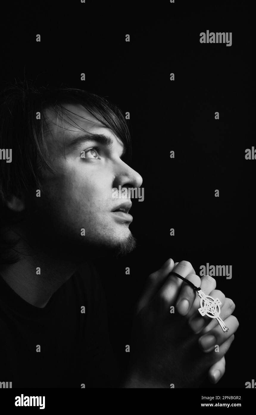 Handsome young man praying in Black and White Stock Photos & Images - Alamy