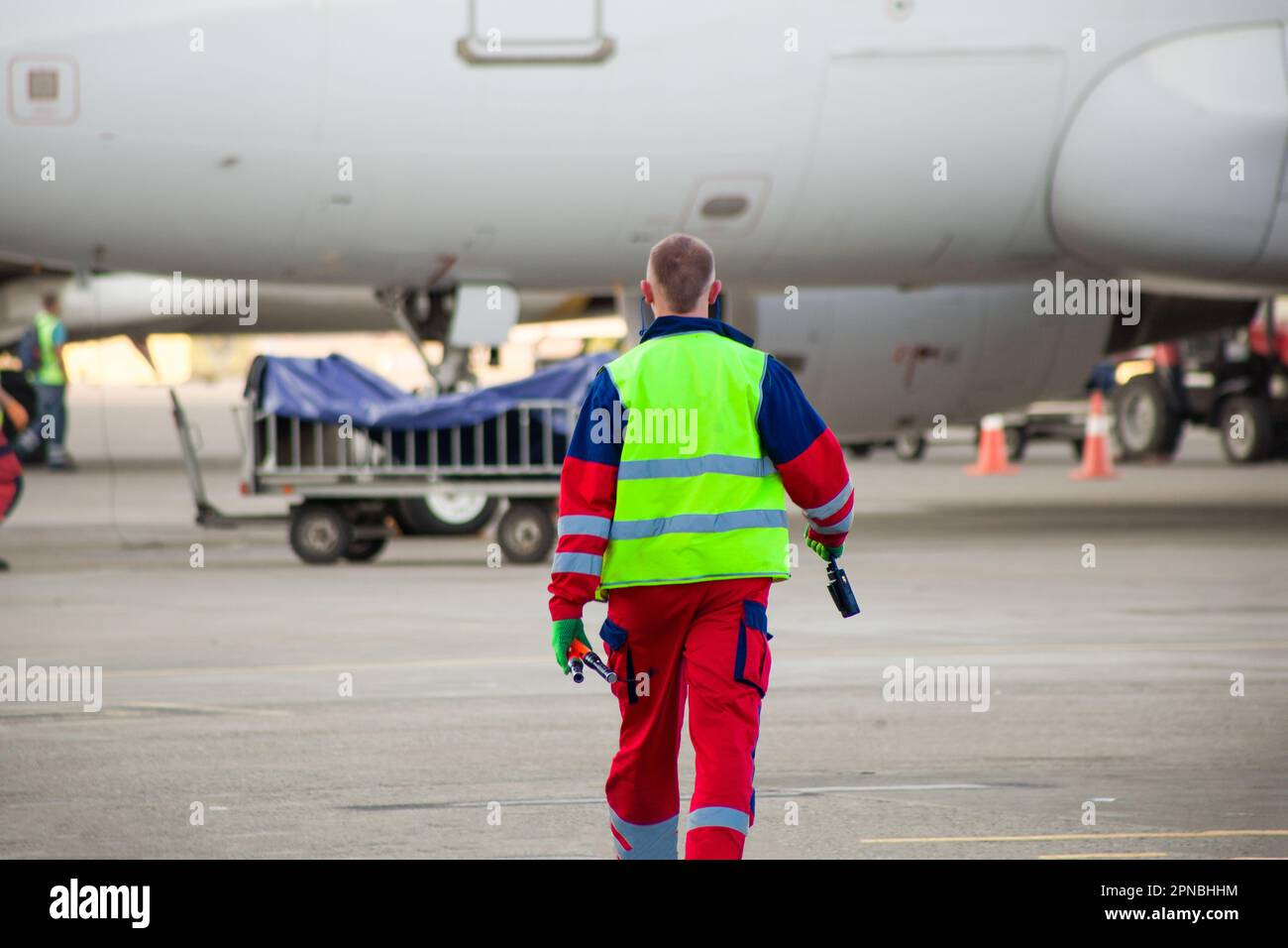 Airport marshaller worker back view. Plane service. Airport life. Aircraft ground handling. Man ...