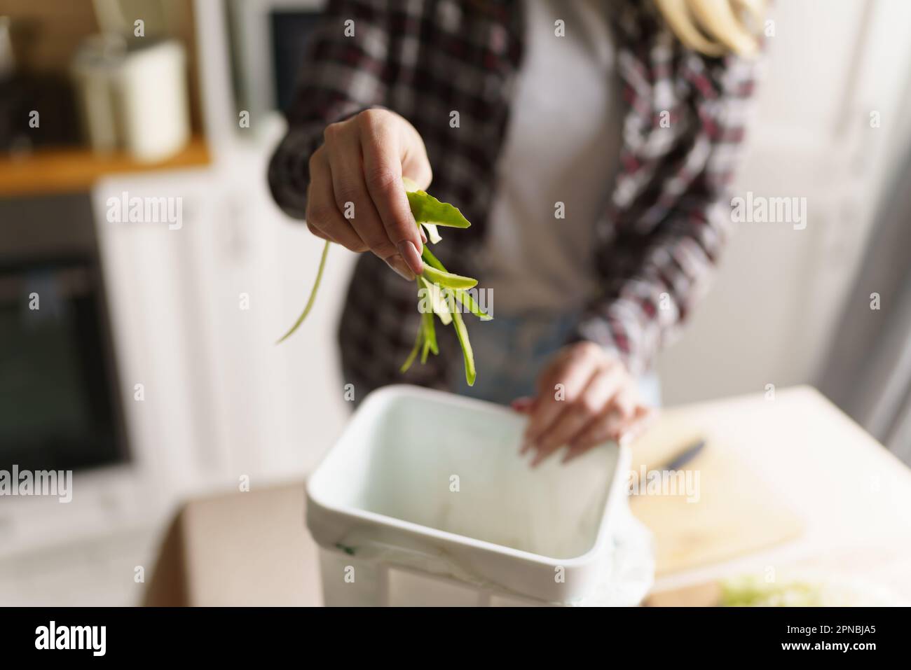 Female hand throwing food peels in a compost bin for fermentation ...