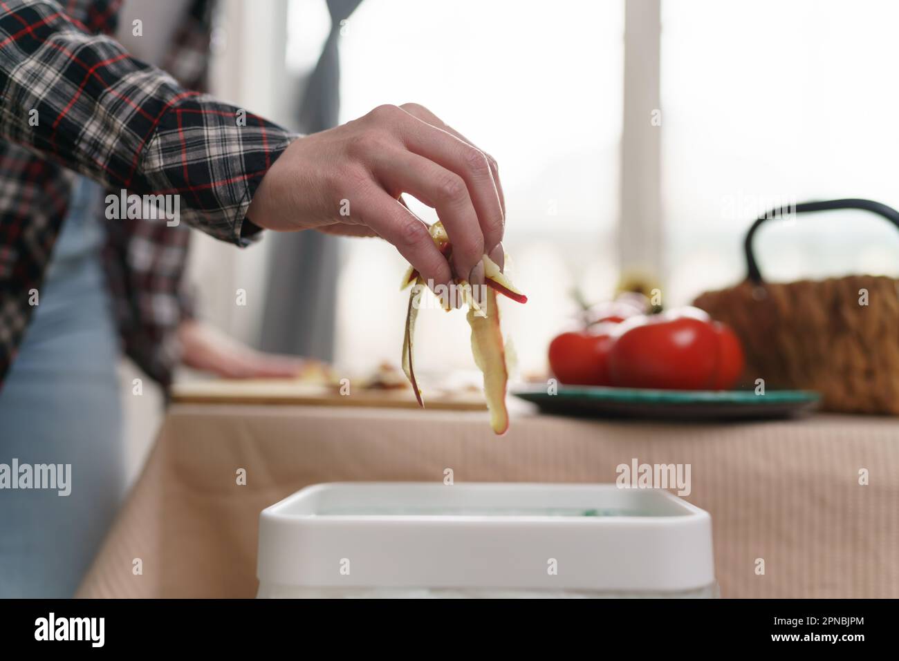 Woman throwing organic food waste in a compost bin for decomposition ...