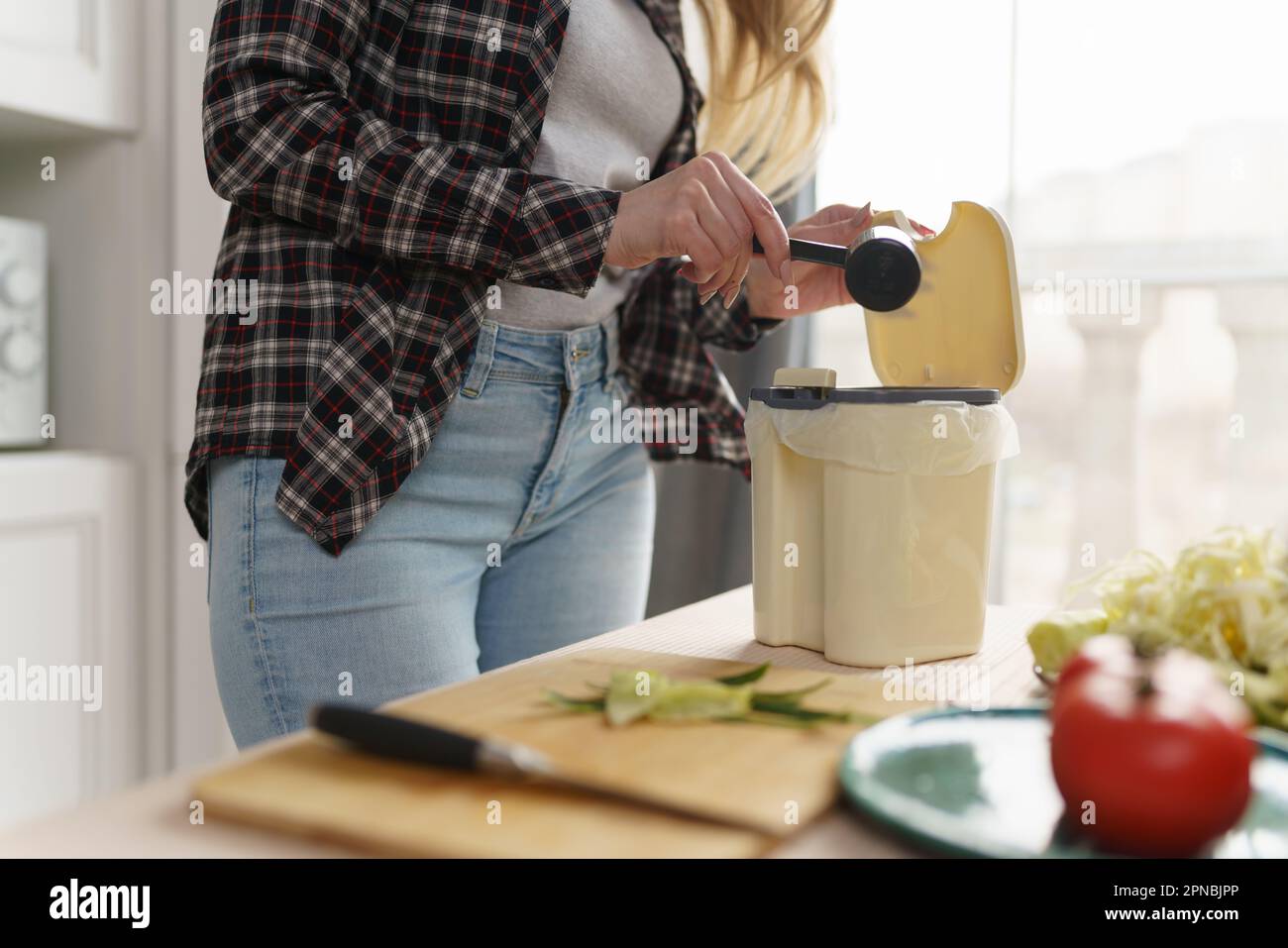 Responsible female person recycling organic food waste in a compost bin ...