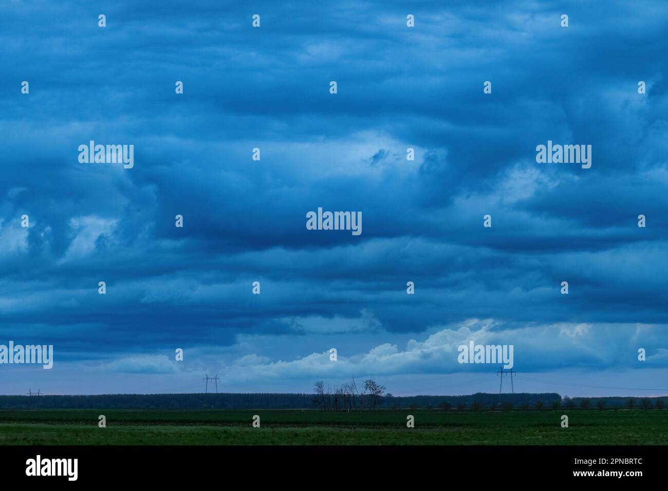Heavy storm clouds at sky above countryside landscape in dusk. Rain ...