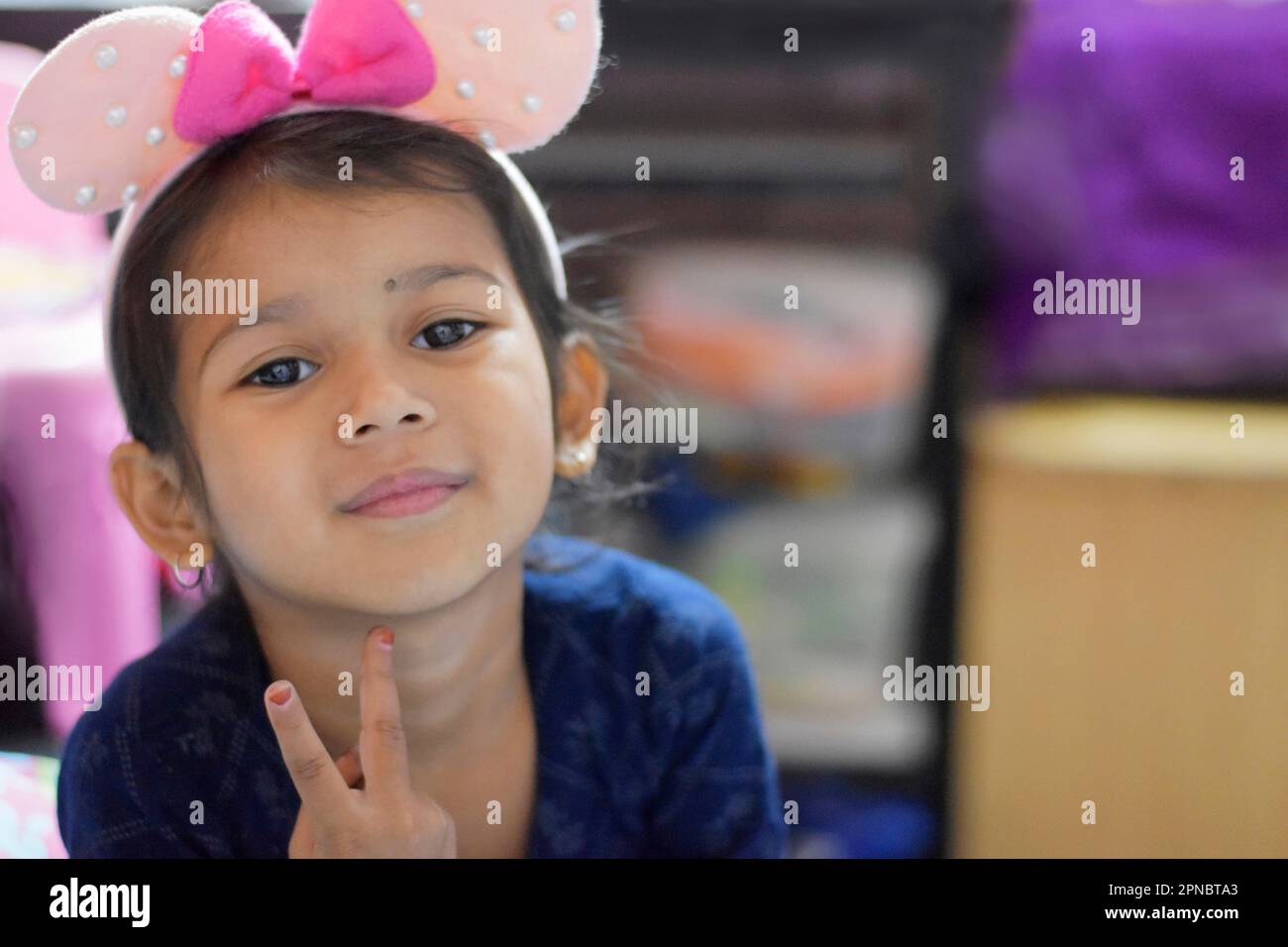 Closeup portrait of Little Indian girl facing camera, showing victory ...