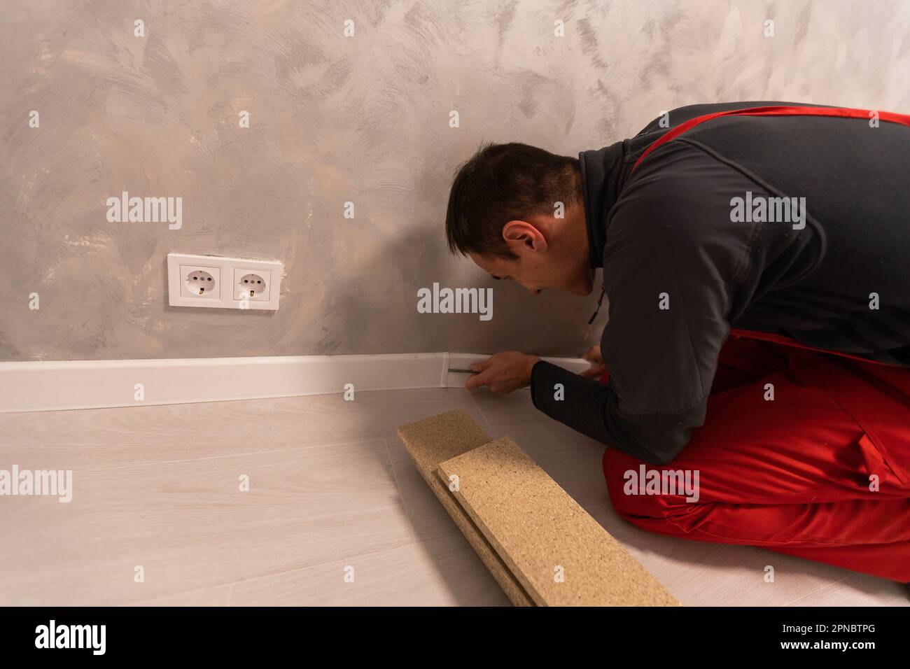 worker installing skirting board, baseboard Stock Photo - Alamy