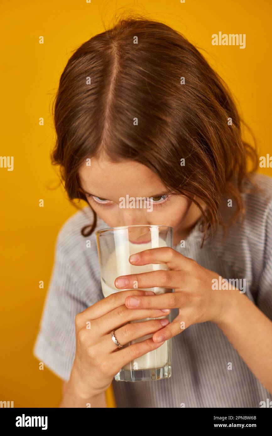 Pretty teen girl, child with a fresh glass of milk isolated on studio ...